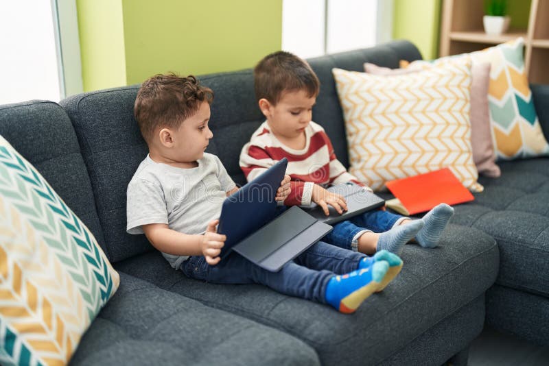 Two Kids Watching Video on Touchpad Sitting on Sofa at Home Stock Photo ...
