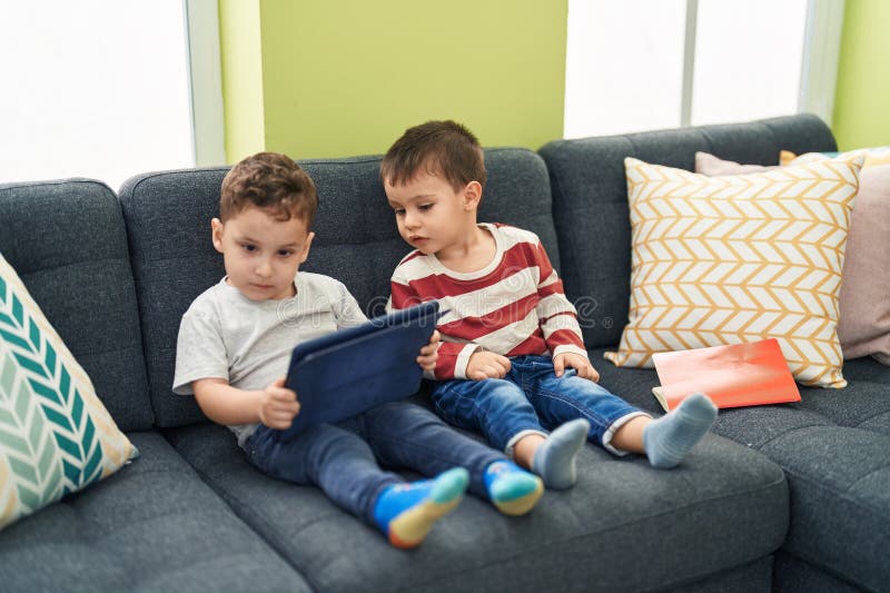 Two Kids Watching Video on Touchpad Sitting on Sofa at Home Stock Image ...