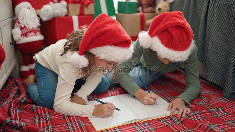 Two Kids Writing on Notebook Sitting on Floor by Christmas Tree at Home ...