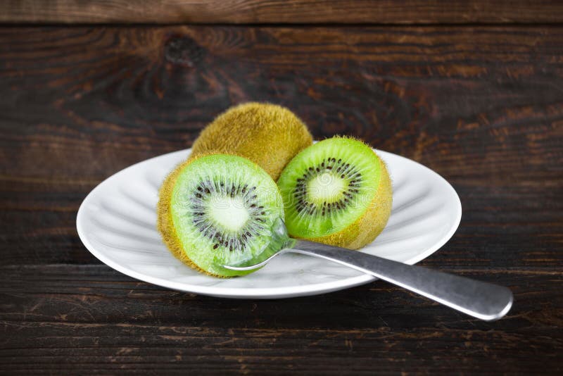Two Kiwi Fruits with Spoon on White Plate, One Kiwi Cut in Half Stock ...