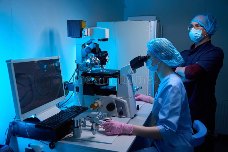 Two Lab Technicians Working with a Microscope and Computer in a ...
