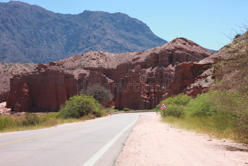 A Two Lane Road Running Down a Slight Slope through the Mountains of ...