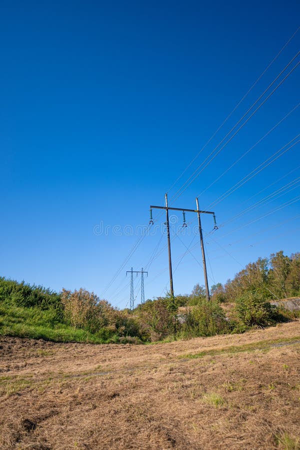 Two Large Electrical High Voltage Pylons Over a Dry Grass Field.. Stock ...