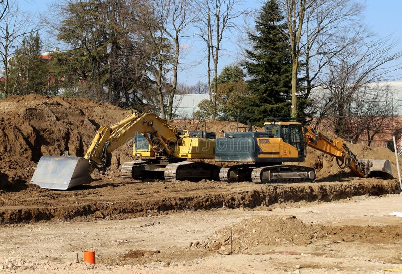 Two Large Excavator at Work among Heaps of Dirt in the Construction ...