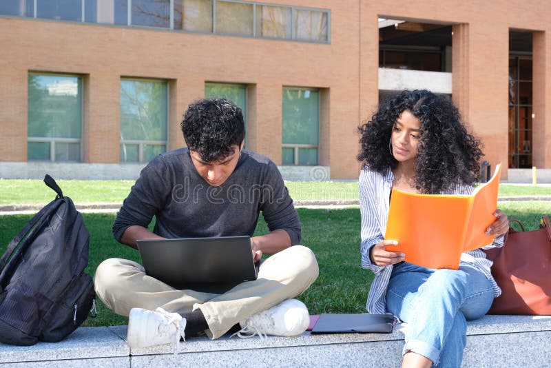 Two Latin Students Studying from Their Lecture Notes Sitting on a Wall ...