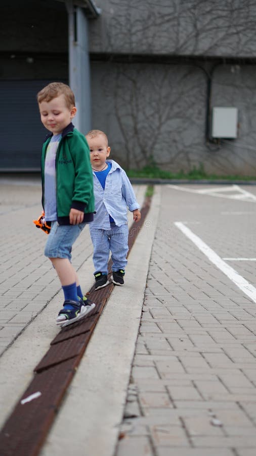 Two Little Boys Walk Along the Path with Drain Grates Stock Image ...