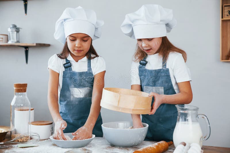 Two Little Girls in Blue Chef Uniform Working with Flour by Using Sieve ...