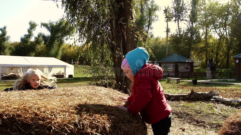 Two Little Girls Having Fun on Haystack. they Jump and Climb Onto it ...