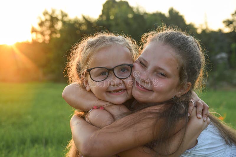 Two Little Girls Sisters Hugging. in the Yard at Sunset Stock Image ...