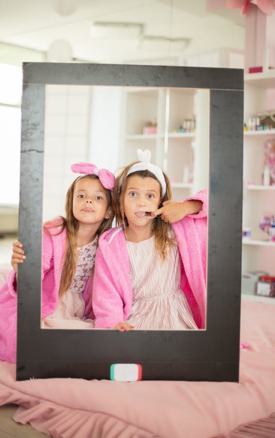 Two Little Girls Sitting on Bed and Holding a Frame. Stock Image ...