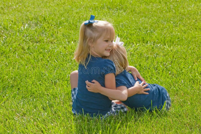 Two Little Girls Sitting in Grass Hugging Stock Image - Image of female ...