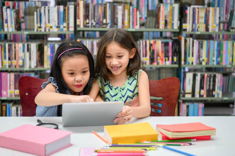 Two Little Happy Cute Girls Playing on a Tablet PC Computing Device in ...