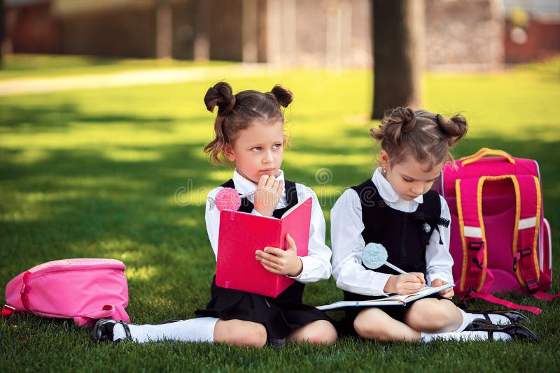 Two Little School Girls with Pink Backpack Sitting on Grass after ...