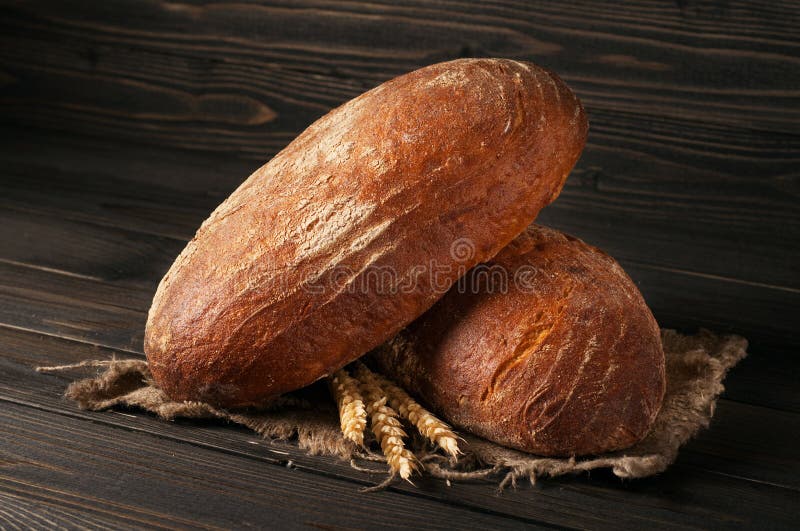 Two Loaves of Bread on a Dark Wooden Background Stock Photo - Image of ...