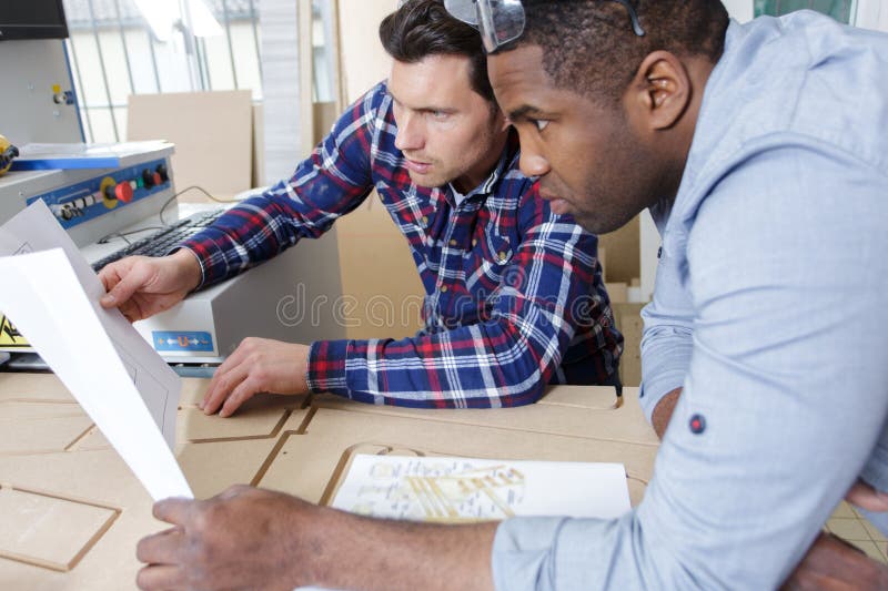 Two Male Colleagues in Factory Looking at Paperwork Stock Image - Image ...