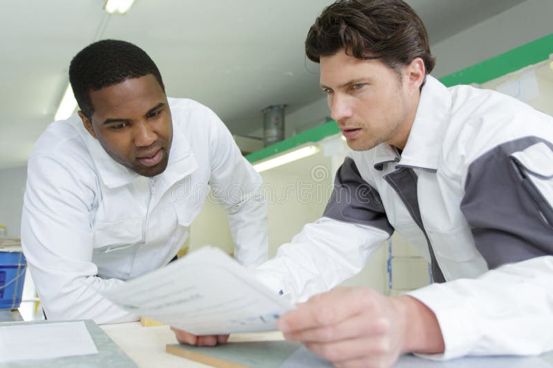 Two Male Contractors Looking at Paperwork Stock Photo - Image of ...