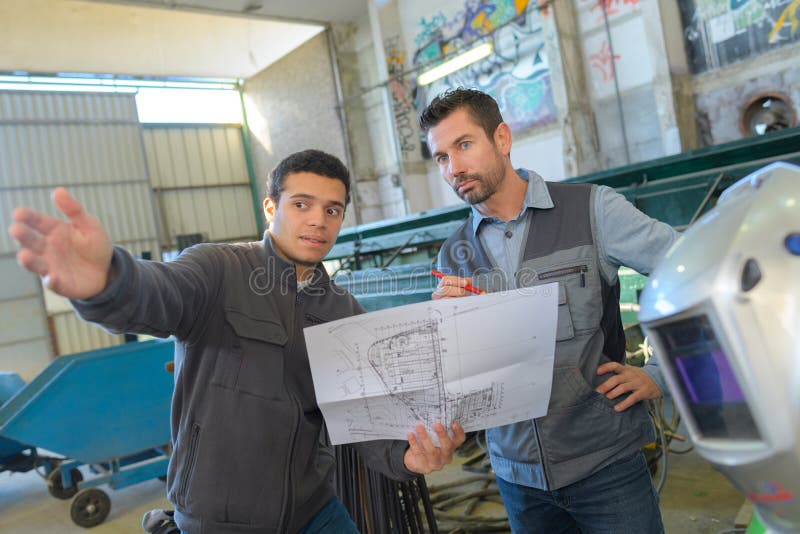 Two Male Engineers in Discussion while Holding Scale Drawings Stock ...