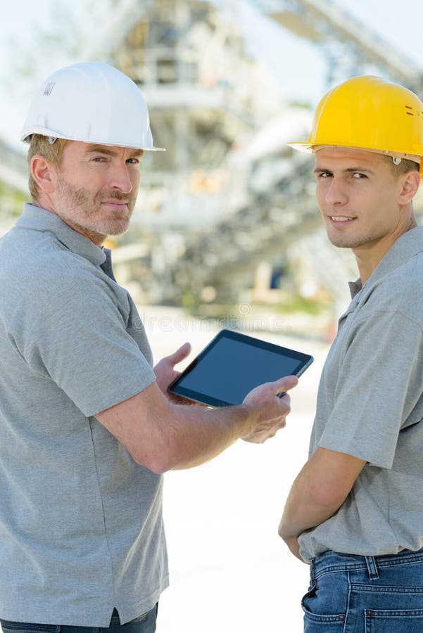 Two Male Engineers Holding Tablet Turning To Look at Camera Stock Photo ...