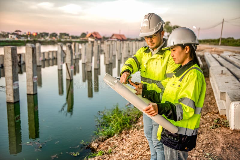 Two Male and Female Engineers are Inspecting the Construction Plans and ...