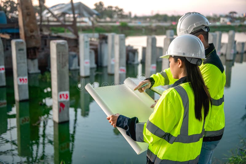 Two Male and Female Engineers are Inspecting the Construction Plans and ...