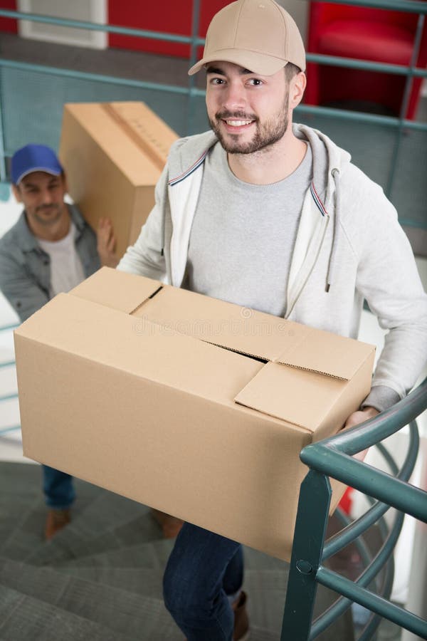 Two Male Movers in Uniform Carrying Cardboard Boxes on Staircase Stock ...