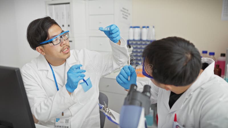 Two Male Scientists Analyzing Chemicals in a Laboratory Using Pipettes ...