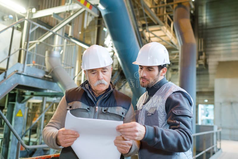 Two Male Workers Looking at Paperwork in Industrial Factory Stock Image ...