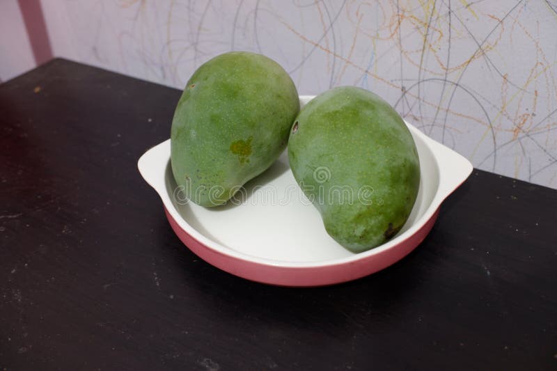Two mangoes on the plate stock photo. Image of green - 306751298