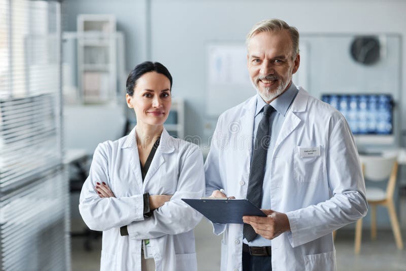 Two Mature Successful General Practitioners in Lab Coats Looking at ...