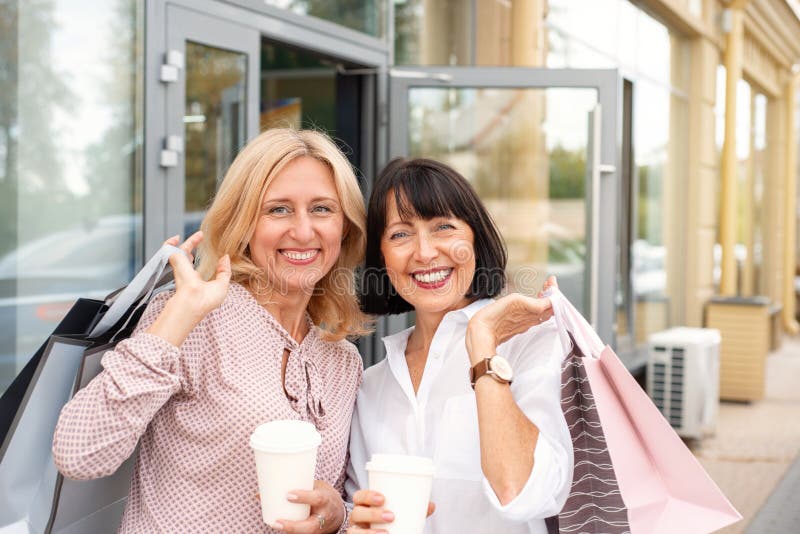 Two Mature Women Having Fun While Doing Shopping And Drinking Coffee