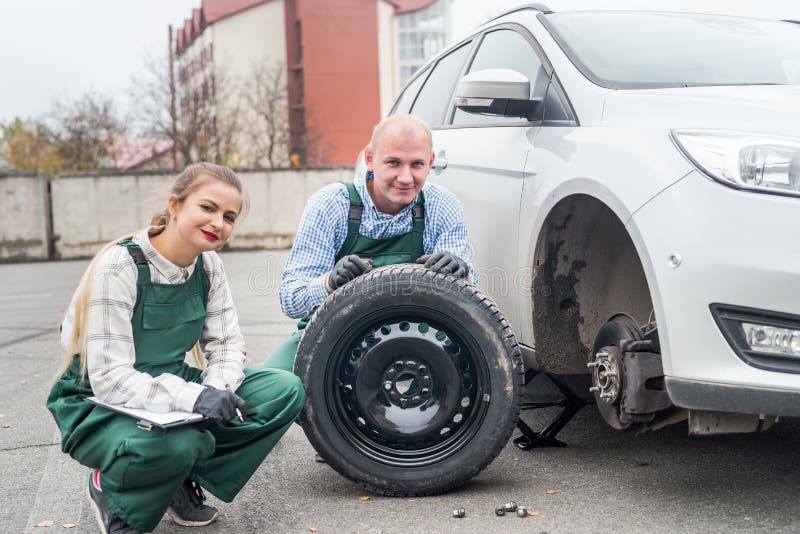 Two Mechanics at Car Service with Spare Wheel Stock Photo - Image of ...