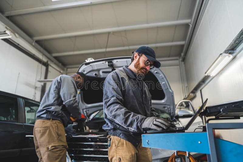 Two Mechanics Making Computer Diagnostics and Checking a Car at the ...