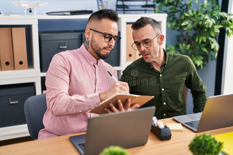 Two Men Business Workers Using Laptop Writing on Notebook at Office ...