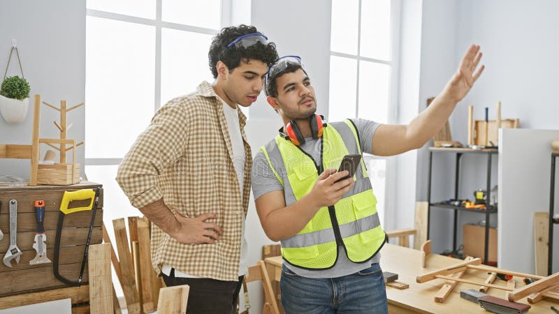 Two Men Collaborate in a Well-lit Carpentry Workshop, Examining a ...