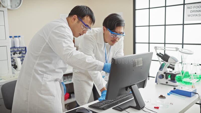 Two Men Collaborating in a Modern Laboratory while Analyzing Data on a ...