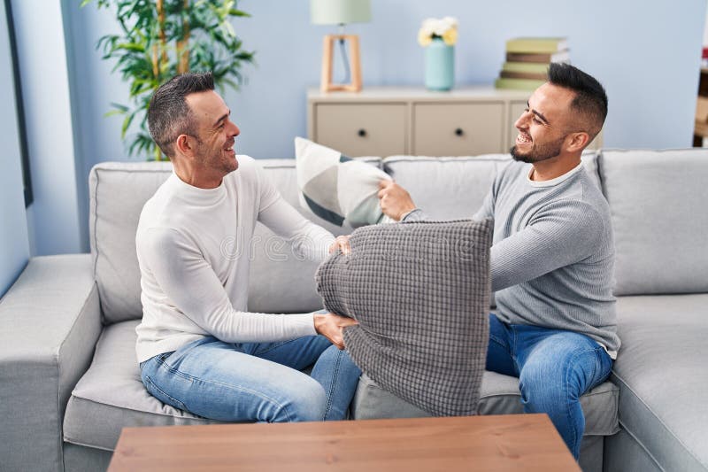 Two Men Couple Fighting with Cushion Sitting on Sofa at Home Stock ...