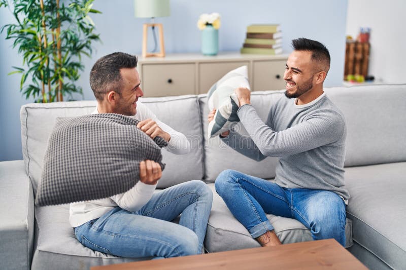 Two Men Couple Fighting with Cushion Sitting on Sofa at Home Stock ...