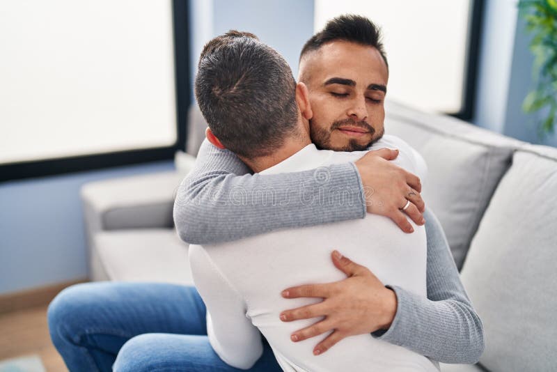 Two Men Couple Hugging Each Other Sitting on Sofa at Home Stock Photo ...