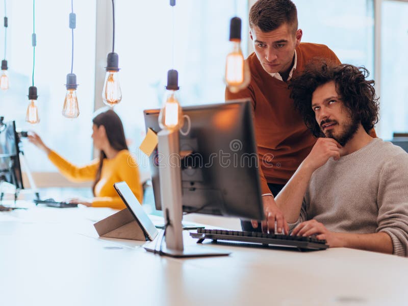 Two Men Discuss a Project while Looking at a Computer Monitor in a ...