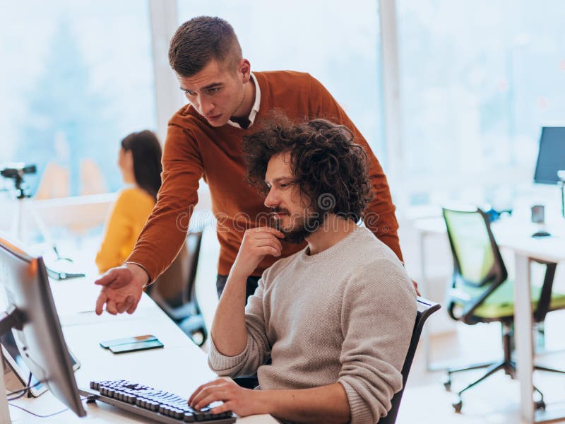 Two Men Discuss a Project while Looking at a Computer Monitor in a ...