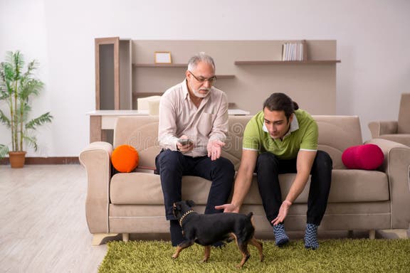 Two men with dog at home stock photo. Image of channels - 212530676