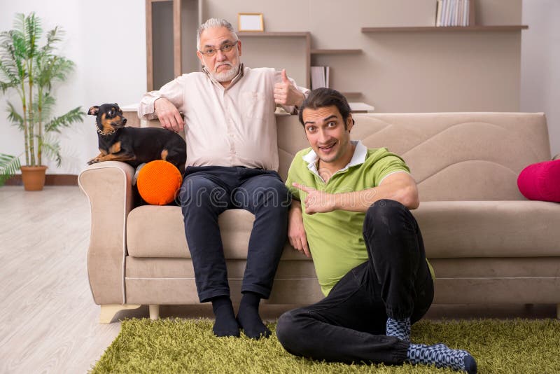Two men with dog at home stock photo. Image of cute - 213285912