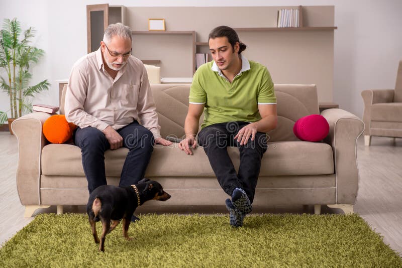 Two men with dog at home stock image. Image of house - 214534015