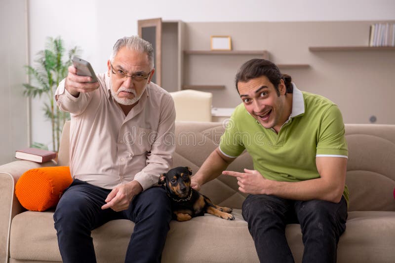 Two men with dog at home stock image. Image of channels - 215700485