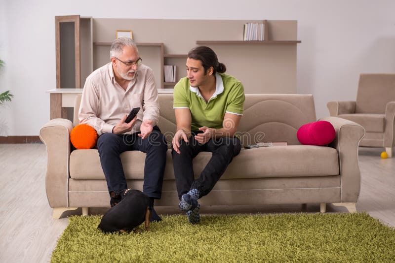 Two men with dog at home stock image. Image of house - 216405495