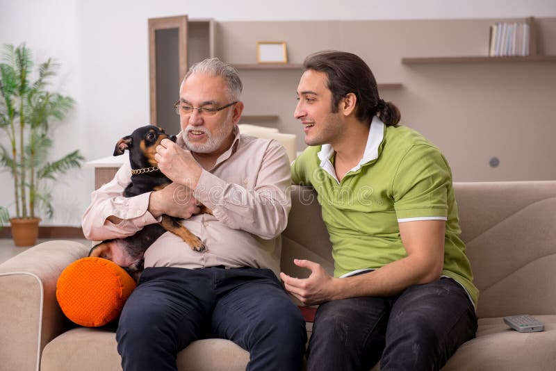Two men with dog at home stock photo. Image of mammal - 217400460