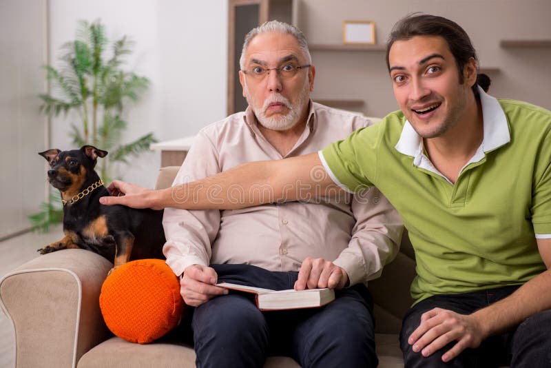 Two men with dog at home stock image. Image of young - 218814891