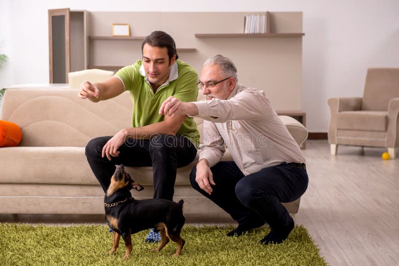 Two men with dog at home stock photo. Image of meal - 215700586