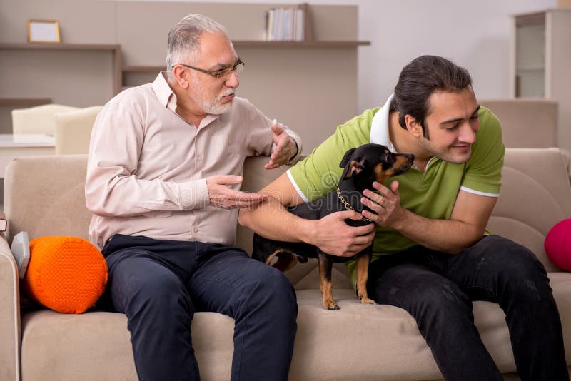 Two men with dog at home stock image. Image of parent - 220629785