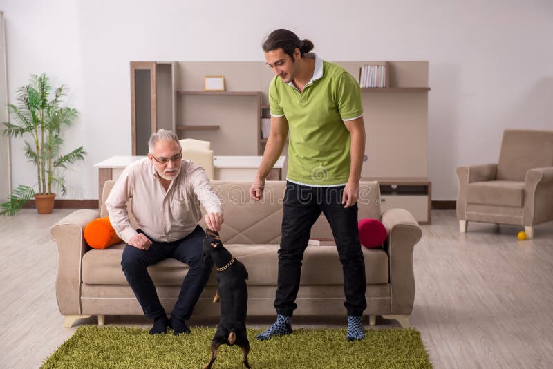 Two men with dog at home stock image. Image of family - 212530799